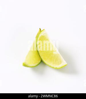 Two lime fruit quarters on white background Stock Photo - Alamy
