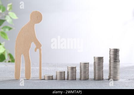 Pension savings. Figure of senior man, coins and green twigs on wooden ...