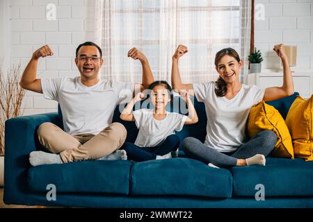 Young parents their child and daughter's biceps muscles shine with ...