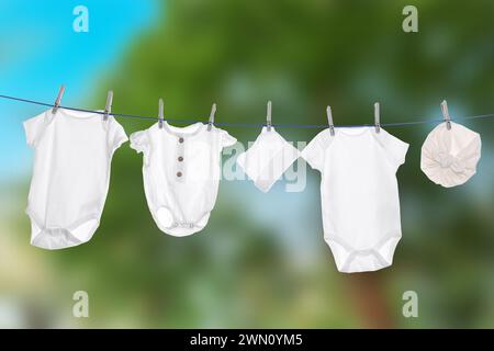 Different baby clothes drying on laundry line against white background ...