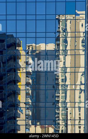 distorted reflection of apartment building in glass wall of skyscraper ...