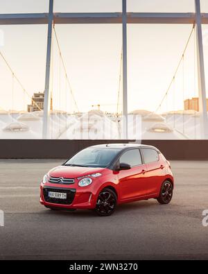 red Citroen C1 in front of modern stadium. Front three quarter view of ...