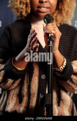 African American female comedian with microphone standing on stage in ...