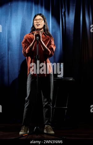 Young female comedian of stand up show pronouncing monologue while ...