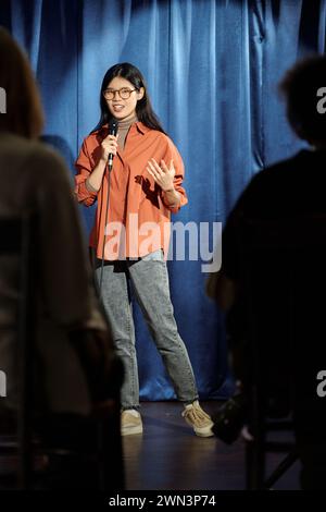 Young Asian female comedian of stand up club standing on stage with ...
