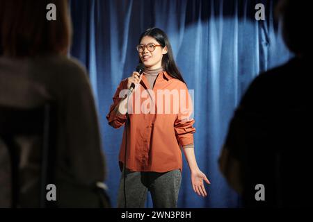 Young Asian female comedian of stand up club standing on stage with ...