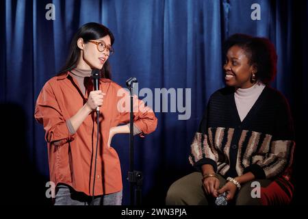 Young Asian female comedian of stand up club standing on stage with ...