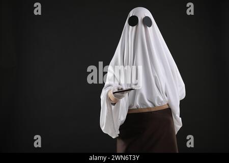 Creepy ghost. Waiter in white sheet and apron with receipt on black ...