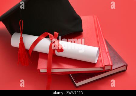 Graduation hat with diploma and notebooks on red background Stock Photo ...