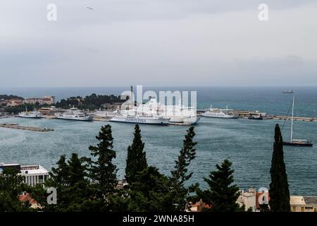 Large Jadrolinija ferry docked under a cloudy sky, with other ships in ...