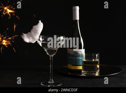 Cocktail with tasty cotton candy and bottle of alcohol drink on dark ...