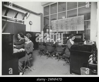 1930s WOMAN TELEPHONE OPERATOR AT SWITCHBOARD LOOKING AT CAMERA SMILING ...