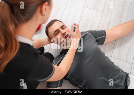 Female trainer with asthma inhaler giving man first aid in gym Stock ...