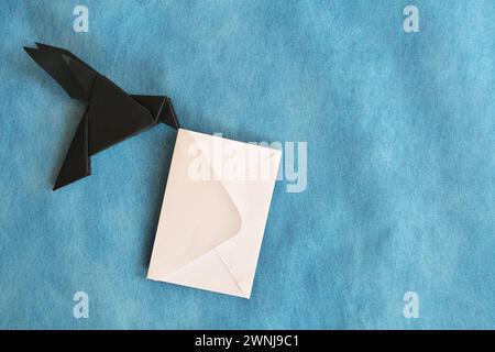 Black raven paper origami carrying white letter envelope. Email ...