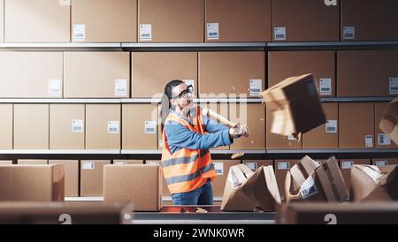 Aggressive rebellious warehouse worker smashing boxes at work, she is ...