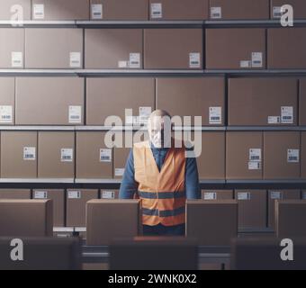 Sad frustrated warehouse worker checking boxes on the conveyor belt ...