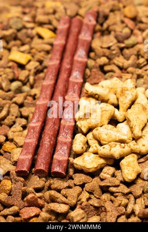 Treats for cats meat sticks sausages against the background of dry food ...