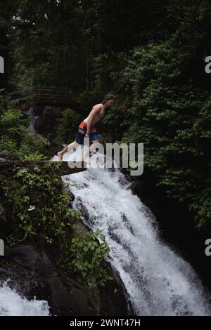 Man jumps from a cliff into the Alin-Alin waterfall. Bali Stock Photo ...