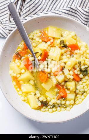 Ptitim with chicken, vegetables and cilantro, white background, top ...