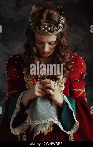 sad medieval queen in red dress with handkerchief and crown crying on ...