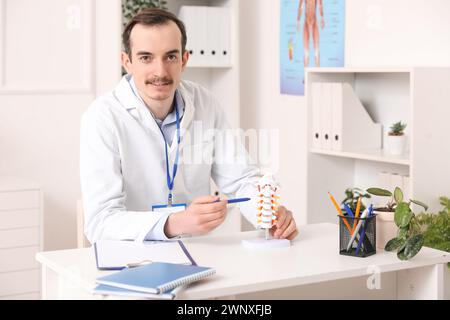 Male doctor demonstrating spinal anatomy with vertebral column model in ...