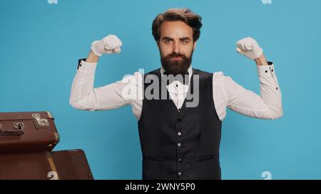 Modern bellboy flexing muscles in studio, showing off strength ...