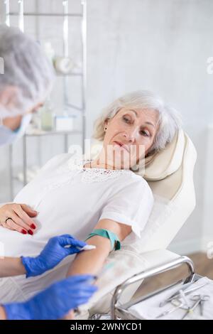 Elderly doctor drawing blood from young patient Stock Photo - Alamy