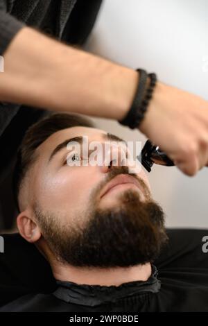 A barber trims a Caucasian client mustache with a trimmer Stock Photo ...