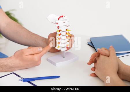 Male doctor explaining spinal anatomy with vertebral column model to ...