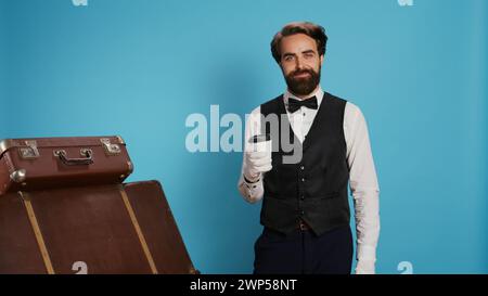 Professional hotel concierge posing on camera against blue background ...