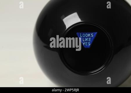 Magic eight ball with prediction Looks Like Yes on light gray table ...