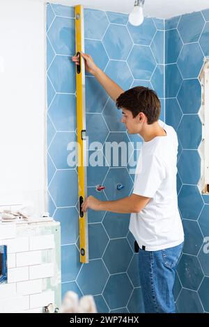 Guy measuring wall flatness with level meter while renovating house ...