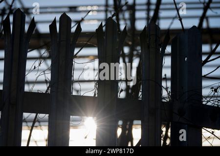 A sunrise behind the silhouette of a construction site with a crane ...