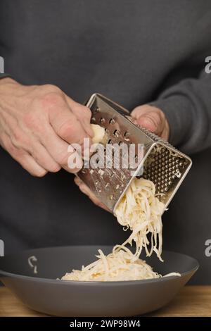 Older man in kitchen grating cheese for spaghetti with minced meat ...