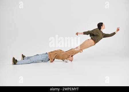 acrobatic woman in casual wear balancing in air with support of her ...