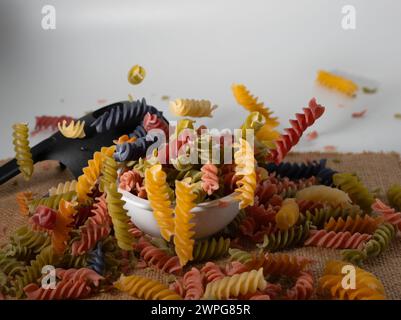 Colorful pasta spread on a table next to utensils Stock Photo - Alamy