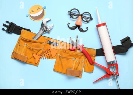 Belt with construction tools, paper fish and funny glasses on blue ...