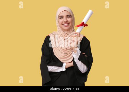 Happy Muslim female graduating student with diploma on green wooden ...