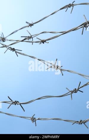 Metal barbed wire on light blue background Stock Photo - Alamy