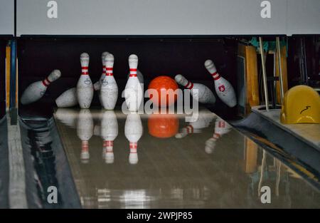 Bowling ball striking and knocking down white pins in the alley. Motion ...