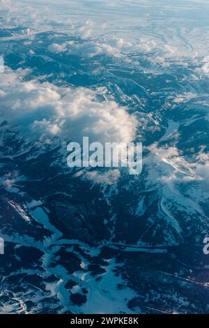 Flying over snow capped mountains in early morning light Stock Photo ...
