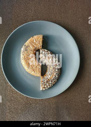 A bagel is cut in half with the underside and the top side with seeds ...