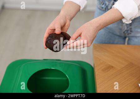 Garbage sorting. Woman throwing muffin liner into trash bin indoors ...