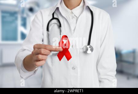 Cancer awareness. Doctor holding red ribbon on blurred background ...