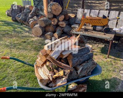 Firewood in a wheelbarrow after splitting with log Stock Photo - Alamy