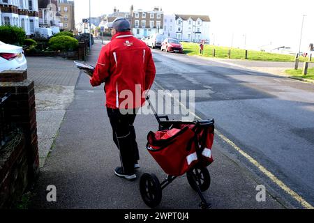 March 2024 - Royal Mail postman pushing his trolley up a hill in the ...