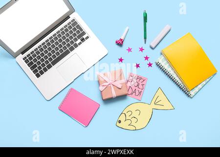 Laptop, gift box, notebooks and sticky notes on blue background. April ...