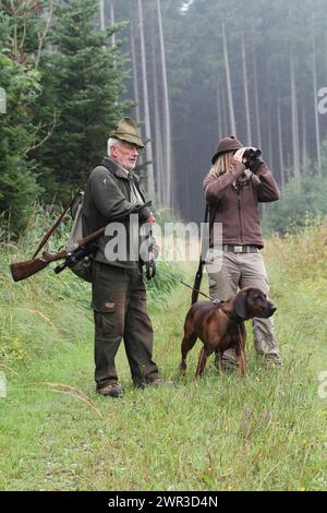 Huntsman and huntress, accompanied by hunting dog Bavarian Mountain ...