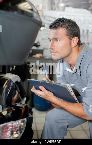 Confident of mechanic writing notes on clipboard Stock Photo - Alamy