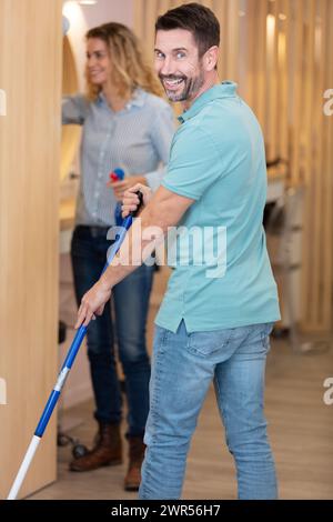 Man wiping floor with the mop. Janitor male washing the dirty floors ...